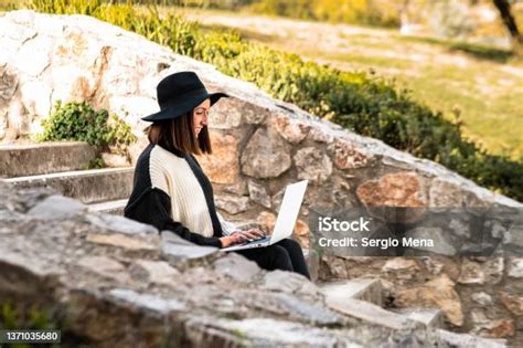그녀의 컴퓨터에서 작업 공원에서 계단에 앉아 모자를 입고 귀여운 쾌활한 백인 여성 여자에 대한 스톡 사진 및 기타 이미지