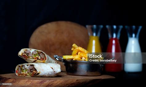 치즈 토마토 붉은 색과 피망과 얇은 라바시 빵에 압연 전통 터키 어 도너 케밥 도너 케밥은 감자 튀김 겨자 케첩 마요네즈와 함께 나무 도마위에 나옵니다 0명에 대한 스톡