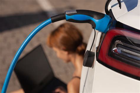 그녀의 전기 자동차가 충전하는 동안 지상에서 기다리고 소녀 랩톱 컴퓨터에서 작업하기 20 24세에 대한 스톡 사진 및 기타 이미지 20 24세 교통수단 급유 Istock