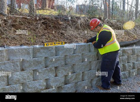 Man Leveling Tool Building Retaining Concrete Block Wall With Being Built On New Property Stock