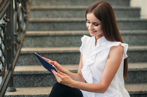 계단에 젊고 매력적인 여성 앉아 하 고 태블릿을 사용 합니다 여자는 태블릿에서 온라인 게임을 재생 개발에 대한 스톡 사진 및 기타 이미지 Istock