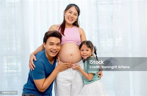 아시아의 아버지와 어린 딸이 임신한 어머니의 배를 껴안고 어루만지며 하얀 커튼 앞에서 웃는 얼굴로 행복을 표현합니다 35 39세에 대한 스톡 사진 및 기타 이미지 Istock