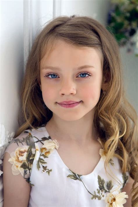 Portrait Of A Girl Seven Years Old With Blond Hair And White Dress