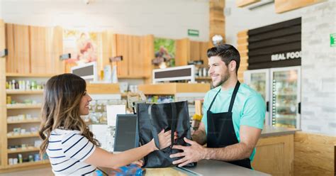식료품점의 계산대에서 여성에게 가방을 주는 자신감 있는 남성 계산원 사진 Unsplash의 쇼핑 이미지