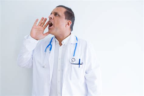 청진 기 및 의료용 코트를 착용 한 중 나이 닥터 남자가 흰 바탕을 외치 며 입에 손을 대 고 큰 소리로 비명을 지 었 다 통신 개념입니다 감정에 대한 스톡 사진 및 기타