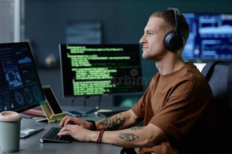 Male Programmer In Headphones Using Computer Working On Code