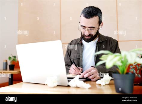 Concentrated Man In Glasses Taking Notes Writing Information From