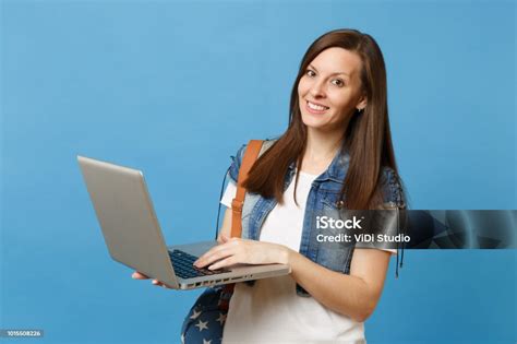 배낭 들고와 작업을 사용 하 여 노트북 Pc 컴퓨터 파란색 배경에 고립에 데님 옷에 예쁜 젊은 여자 학생의 초상화 대학에서 교육입니다 광고에 대 한 공간을 복사 합니다 20
