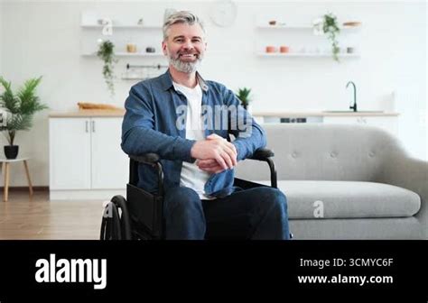 Portrait Of Smiling Mature Man In Casual Attire Sitting In Wheelchair