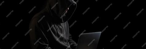 premium ai image hacker without face in a hood holds a laptop on a