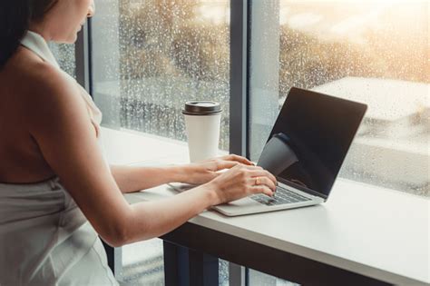 사무실 창문 옆에 있는 카페 테이블에 앉아 있는 동안 랩톱 컴퓨터를 사용하는 젊은 비즈니스 여성 건축물에 대한 스톡 사진 및 기타 이미지 Istock