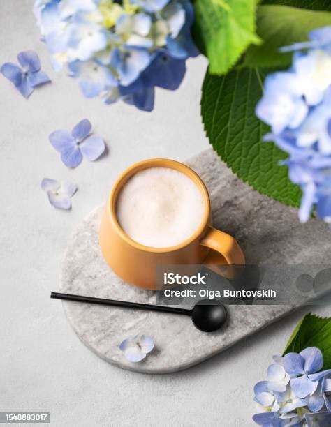 파란 수국 꽃과 노란 컵에 담긴 카푸치노 커피 한 잔과 밝은 배경에 숟가락이 있는 봄 꽃다발 아침 식사로 아침 음료의 개념 꽃 식물에 대한 스톡 사진 및 기타 이미지