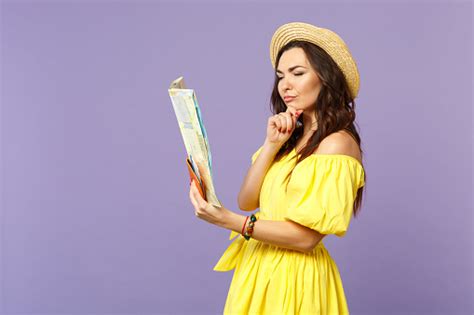 노란 드레스에 잠겨있는 젊은 여자 여름 모자 개최 도시 지도 파스텔 바이올렛 벽 배경에 고립 된 여권 탑승권 티켓 사람들은