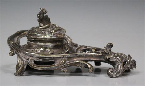 A Late 19th Century Continental Plated Inkstand Of Rococo Scroll Form The Rim Cast As The Head And A Late 19th Century Continental Plated Inkstand Of Rococo Scroll Form The Rim Cast As The Head And