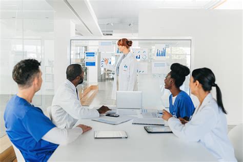 의료 프리젠 테이션 지도자를 듣는 의사 및 간호사는 병원 회의실에서 통계 그래프 및 인포 그래픽 연구에 대해 이야기합니다 의료