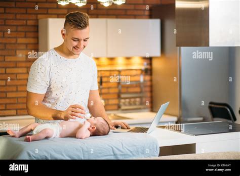 Dad Trying To Work While Standing With His Newborn Babe In Home Office Interior Stock Photo Alamy