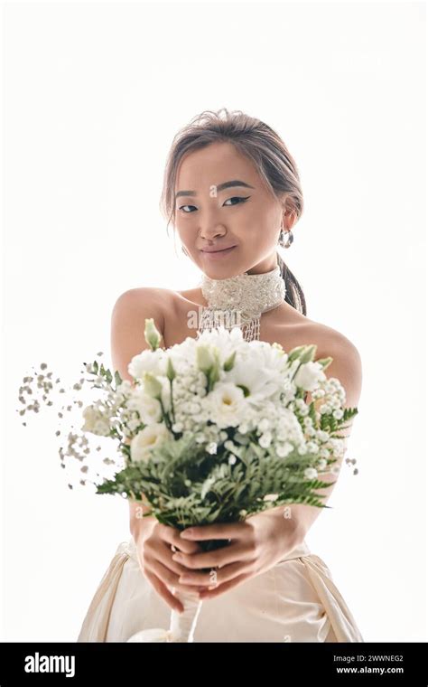 Attractive Young Asian Woman With Grace Makeup Hold Out Bouquet Of White Flowers On Light