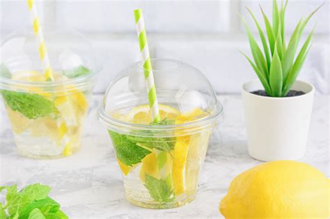 신선한 클렌징 육즙 레몬 민트 잎 디톡스 워터 레모네이드 다과 청량 음료는 밀짚과 함께 유리로 제공됩니다 흰색 테이블 배경에 홈 공장입니다 채식주의 자 건강한 해독 음료 0