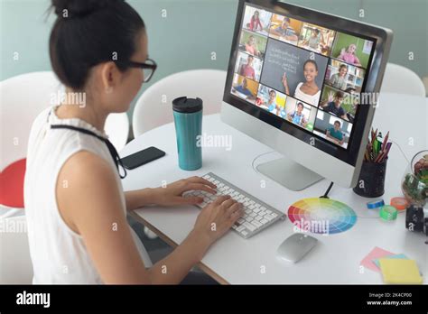 Asian Woman Using Computer For Video Call With Diverse Elementary School Pupils On Screen