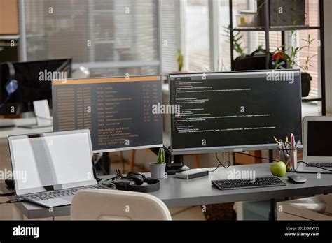 Background Shot Of Empty Programmer Desk Setup With Laptop And Multiple Computer Screens