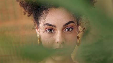 흑인 여성 자연의 아름다움과 유기농 배경을위한 열대 잎 뒤에 메이크업 화장품 미용을위한 녹색 식물로 신선하게 보이는 아름다운 여성 패션 모델의 얼굴 초상화 메이크업 화장품에