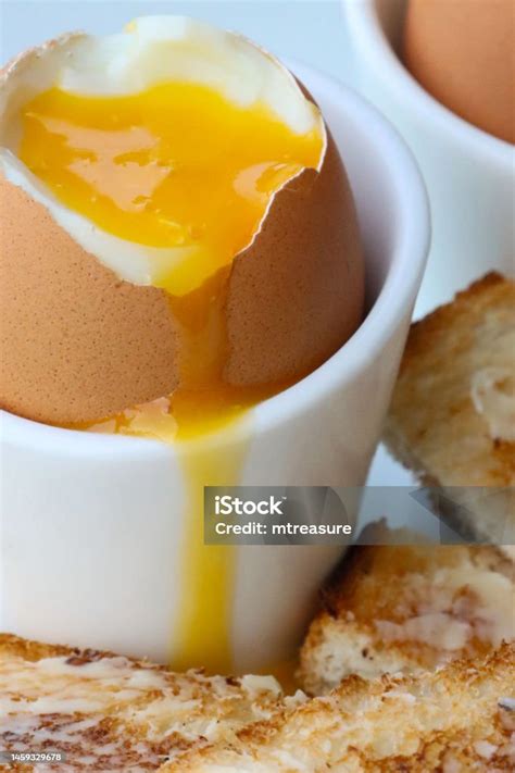 흰색 접시에 달걀 컵에 두 개의 부드러운 삶은 계란을 얹은 버터를 바른 토스트 군인의 전체 프레임 이미지 콧물 노른자를 얹은 부드러운 삶은 계란 전경에 초점 0명에 대한