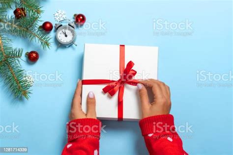 파란색 배경 전나무 나무 크리스마스 Baubles 복사 공간이있는 장난감에 흰색 선물 상자를 여는 빨간색 새해 스웨터에 여성의 손 플랫 레이 시계 크리스마스에 대한 스톡