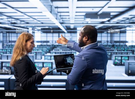 Team Of Technicians In Data Center Using Laptop To Visualize Artificial
