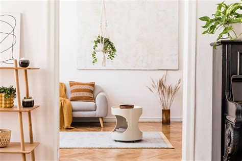 디자인 커피 테이블 회색 소파 꿀 노란색 베개 피아노 나무 선반 식물 및 우아한 개인 액세서리가있는 아늑한 아파트의 세련된