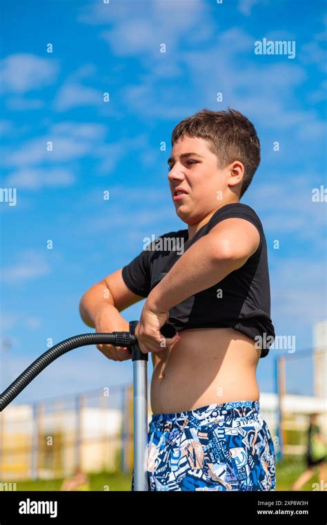 An Enthusiastic Guy Is Diligently Pumping An Inflatable Sup Board Stock