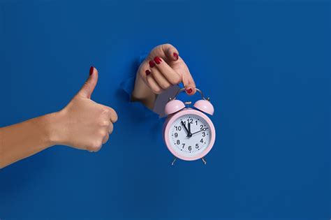 찢어진 어두운 파란색 종이 벽 모형을 통해 손에 핑크 알람 시계 텍스트의 공간을 복사합니다 시간이 부족합니다 실패 기한 스트레스 아웃 시간 관리 및 규율의 개념 0명에 대한