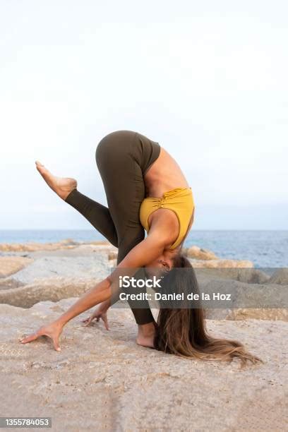 바다 근처의 바위에 균형 요가 아사나를하고 젊은 여자 전방 접기 우타나사나 변형 세로 복사 공간 요가에 대한 스톡 사진 및 기타 이미지 Istock
