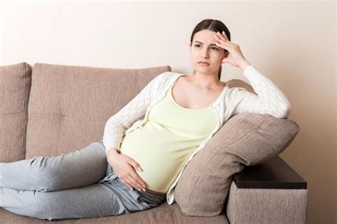 Young Pregnant Woman With Headache Sitting On Sofa Pregnancy