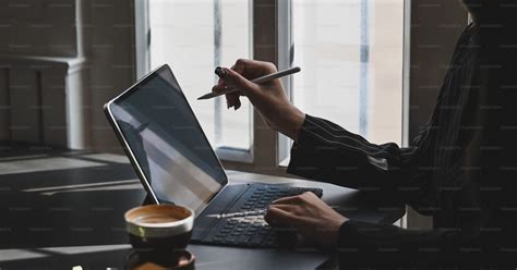 젊은 임원 여성은 고급 사무실을 배경으로 현대적인 작업 책상에서 일하는 것에 대해 생각하면서 컴퓨터 태블릿에 전기 펜을 가리키고 있습니다 사진 Unsplash의 테이블 이미지