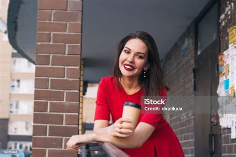 거리에서 음료의 테이크 아웃 컵을 들고 빨간 드레스에 빨간 립스틱과 아름다운 젊은 여자 거리에 대한 스톡 사진 및 기타 이미지