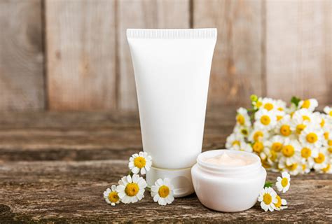 밝은 배경에 카모마일 꽃이 있는 얼굴 몸 손을 위한 보습 크림 병을 엽니다 한방 피부과 화장품 위생 크림 천연 화장품 아름다움 개념입니다 모형 0명에 대한 스톡 사진 및