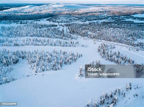 핀란드의 산 눈 덮인 숲 얼어 붙은 호수 및 겨울 도로가있는 눈 겨울 풍경의 공중 보기 핀란드 라플란드에 대한 스톡 사진 및