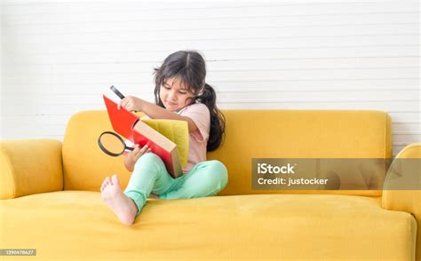 소파에서 돋보기로 책을 읽는 어린 아이 소녀 거실에서 돋보기를 가지고 노는 행복한 아이들 4 5세에 대한 스톡 사진 및 기타 이미지 4 5세 검색 공부 Istock