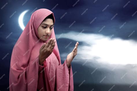 밤 장면을 배경으로 손을 들고 기도하는 동안 베일을 쓴 아시아 이슬람 여성 프리미엄 사진