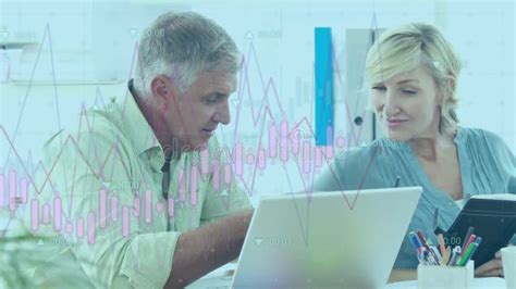 Analyst Typing And Pointing Colleague Writing Notes For Finance Review With Pulsing Graph