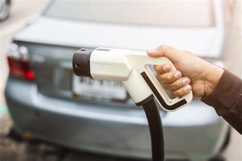 Ev 자동차 주차장에서 충전 하는 전기 자동차 전기 자동차 충전소에 연결된 전원 케이블 공급 장치를 들고 있는 남성 손