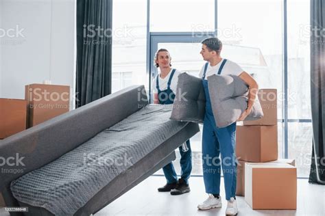 무거운 소파를 들고 방에서 실내에서 일하는 파란색 유니폼을 입은 두 명의 젊은 이주 20 24세에 대한 스톡 사진 및 기타 이미지 20 24세 25 29세 2명