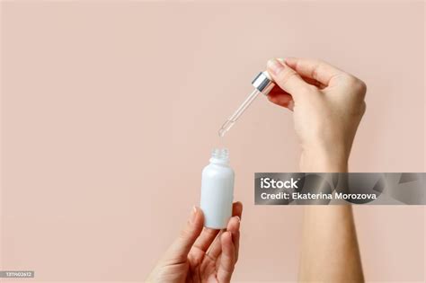 베이지 색 트렌디 한 Neautral 지구 톤 배경에 얼굴 에센셜 오일 이나 세럼 포장을 들고 여자 손 스킨케어 컨셉 카피 스페이스 뷰티 살롱 전단지용 뷰티 화장품 제품