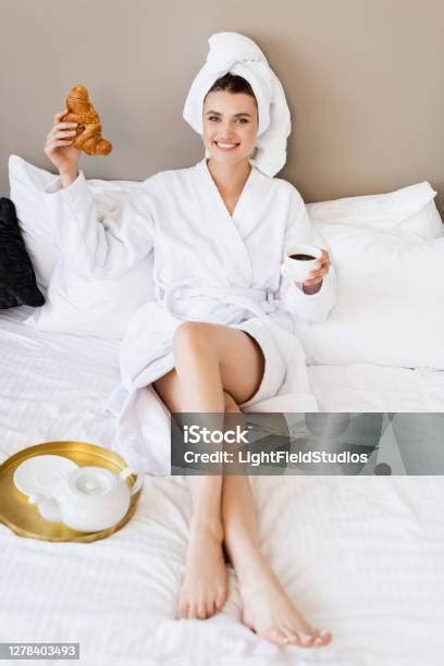 침대 에 아침 식사 트레이 근처 크루아상과 커피 한 잔을 들고 수건과 목욕 가운에 즐거운 여자 20 24세에 대한 스톡 사진 및 기타 이미지 Istock