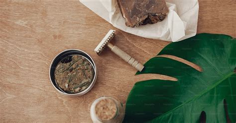 천연 비누 금속 주석의 고체 샴푸 재사용 가능한 면도기 녹색 몬스테라 잎이 있는 나무 배경에 우탄 플라스틱 프리 뷰티 필수품 제로 폐기물 개념 플랫 레이 지속