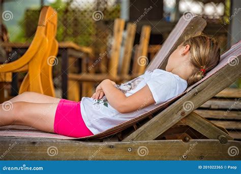 Cute Caucasian Girl Resting On A Reclining Wooden Chair Stock Image
