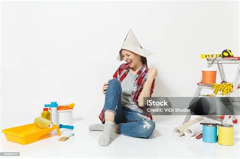 신문 모자 우승자 제스처를 하 고 흰색 배경에 고립 된 재건축 아파트 룸에 대 한 악기와 함께 바닥에 앉아 있는 여자 벽지 액세서리 그림 도구 수리 가정 개념입니다 개선에