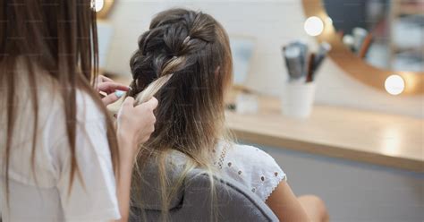 여성 미용사의 뒤에서 두 개의 작은 이삭을 땋아 미용실의 젊은 장발 고객에게 전경 트렌디한 헤어스타일을 하는 과정에서 전문 헤어커터 아름다움과 패션의 개념입니다 사진