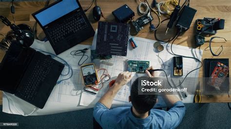 최고 그것은 영의 회로 기판 납땜 하는 기술자 그의 테이블은 다양 한 컴퓨터 부품으로 전체 마더보드 노트북 케이블 아침 태양