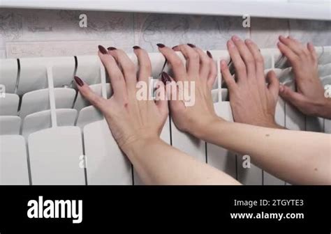 Frozen Male And Female Hands Touch The Home Radiator And Try To Warm Up Home Heating Problem